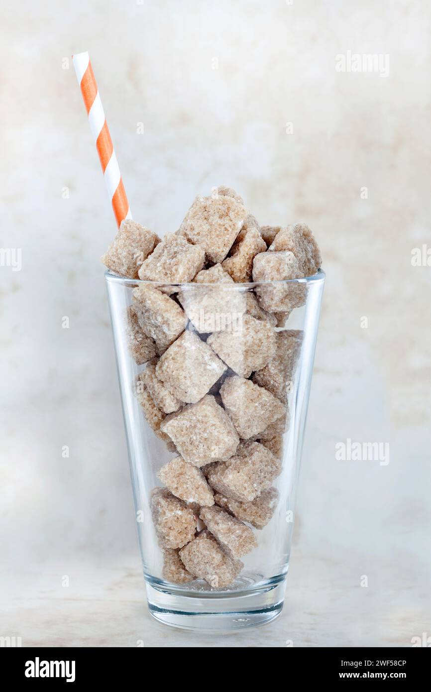 Glass filled with brown sugar cubes and straw Stock Photo - Alamy