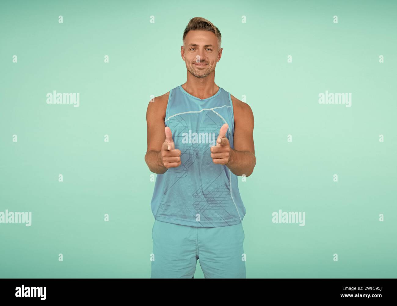 Happy sportsman pointing fingers blue background. Fit sportsman in ...