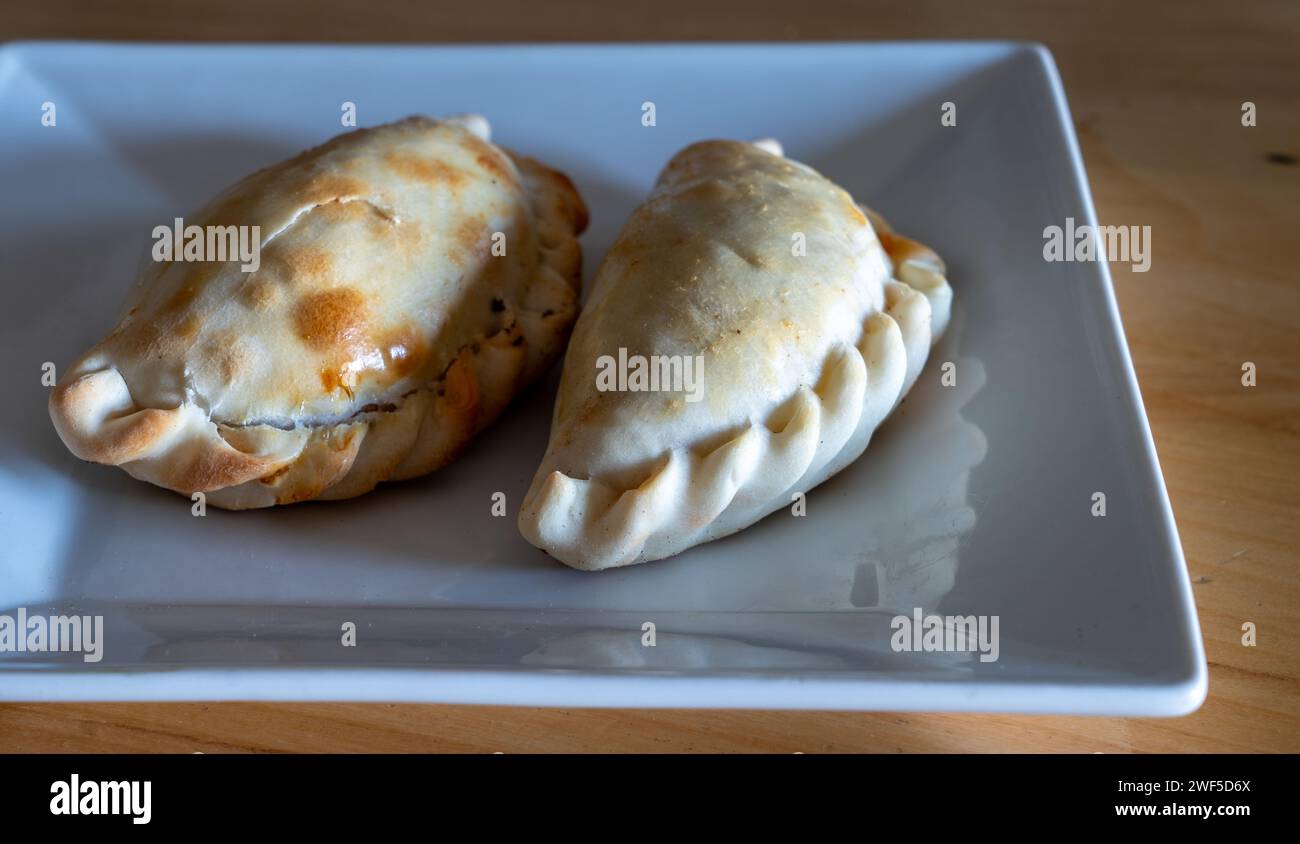 Two empanadas served in a White Square Plate Stock Photo - Alamy