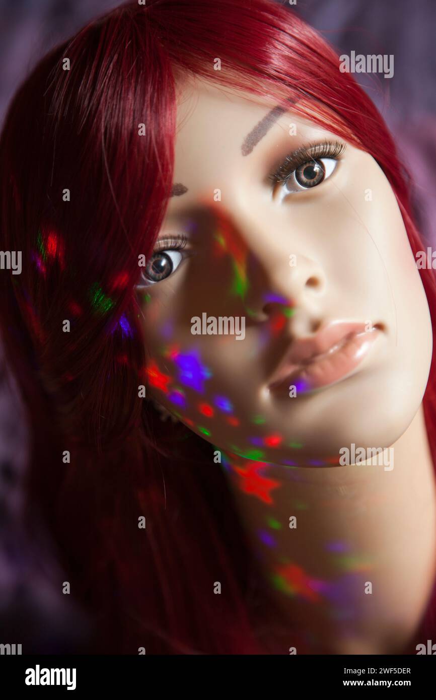 Red haired plastic woman mannequin with colorful stars projected on her ...