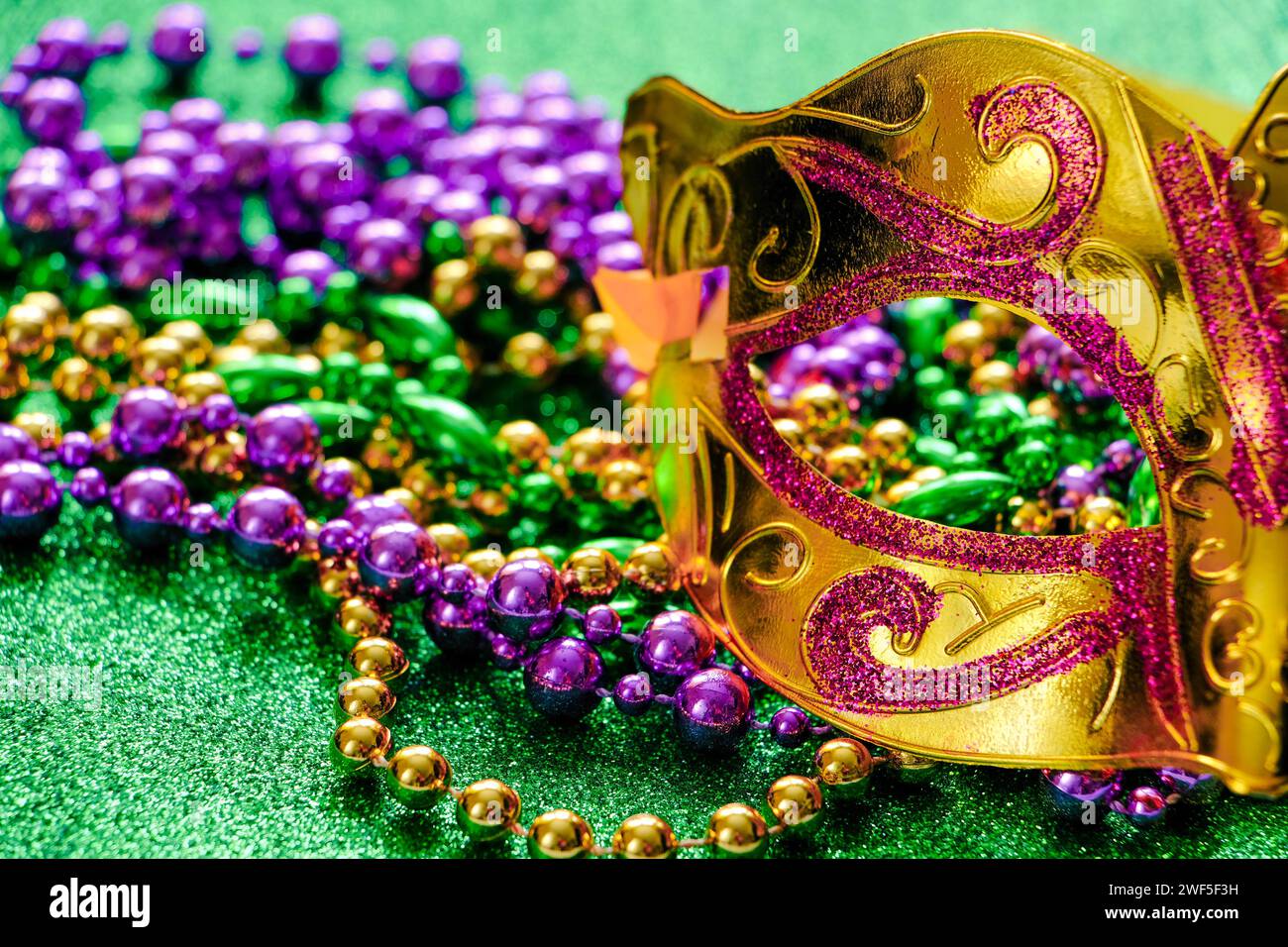 Carnival mask and colorful beads on green shiny background. Mardi Gras ...