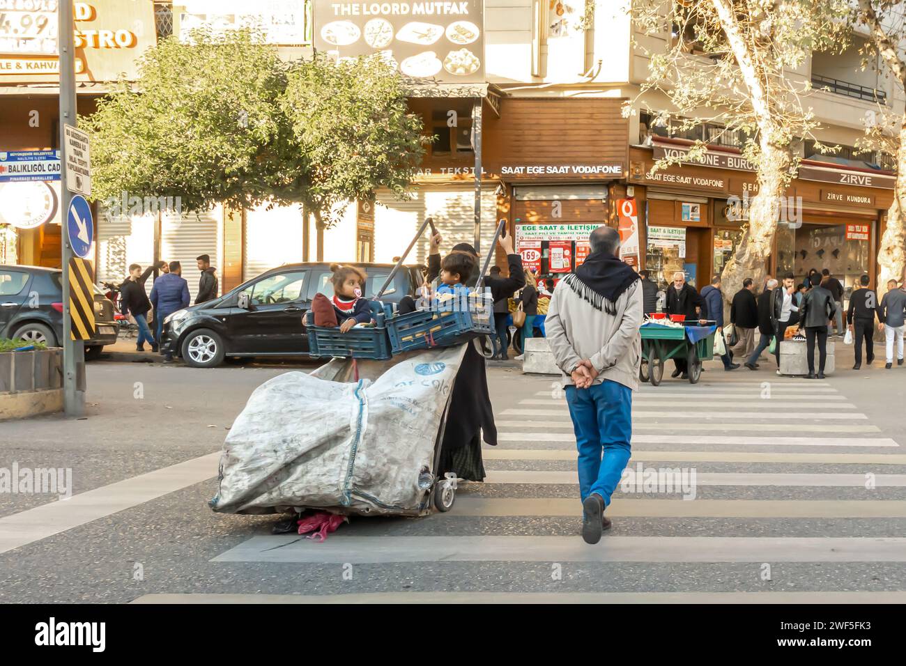 Middle Eastern refugees - a mother and babies using a grabage cart with ...