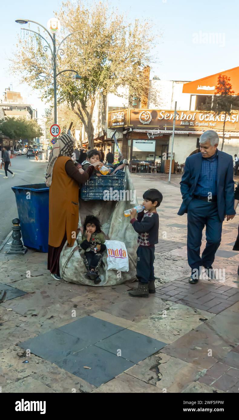 Middle Eastern refugees - a mother and babies using a grabage cart with ...