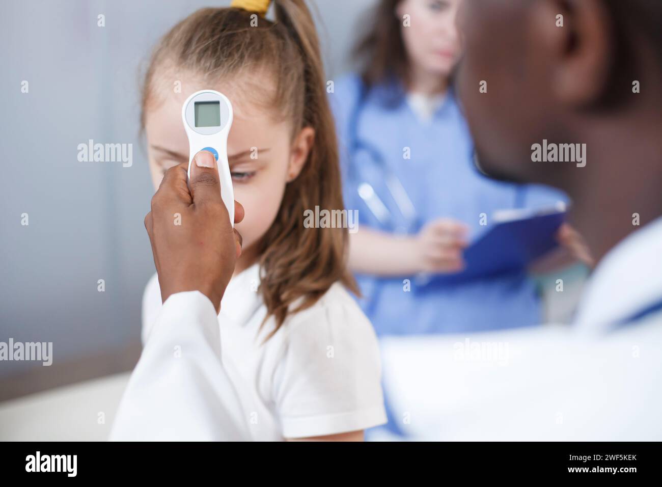 Close-up shot of an African American doctor using a thermometer to ...
