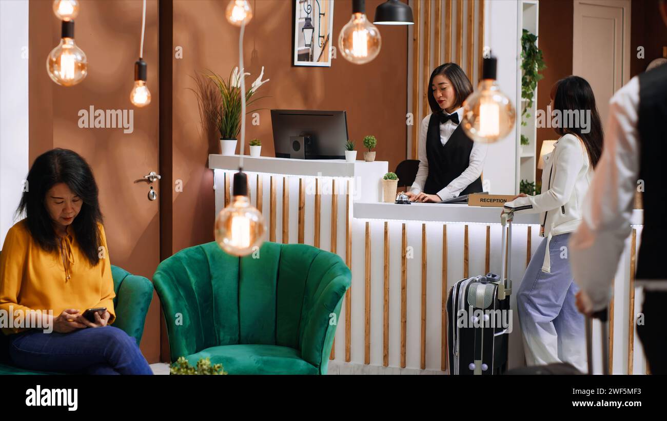 Young traveler arriving at hotel lobby with luggage, receptionist ...