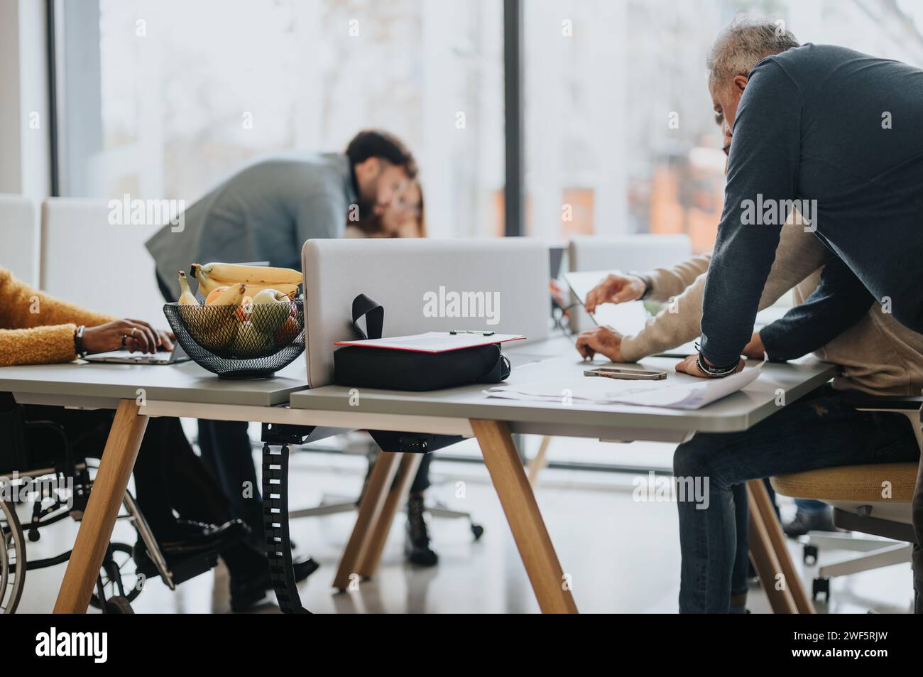 A multi-ethnic group of colleagues collaborate in a well-lit office ...