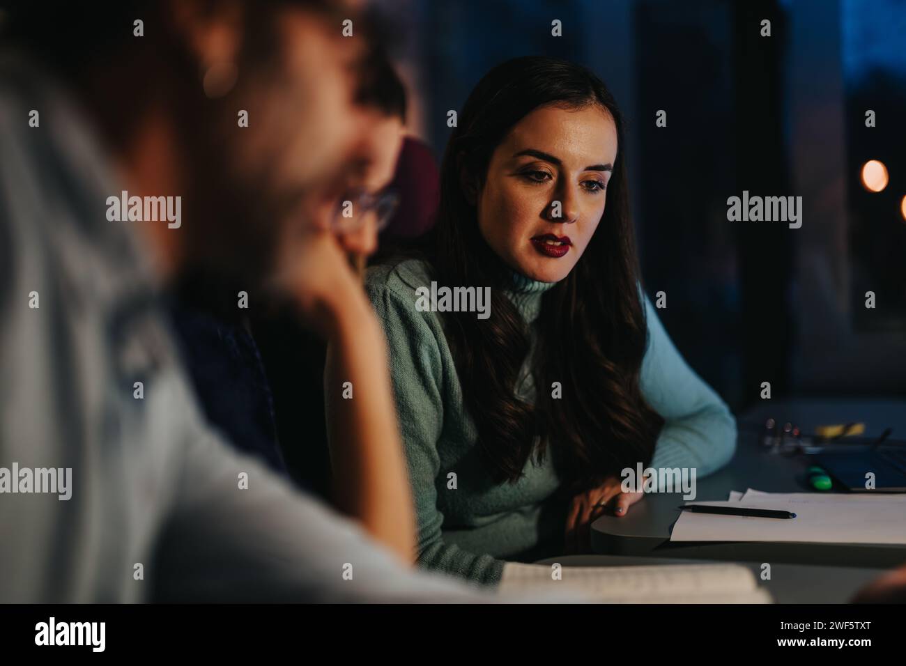 Professional team in deep discussion during a late-night office meeting ...