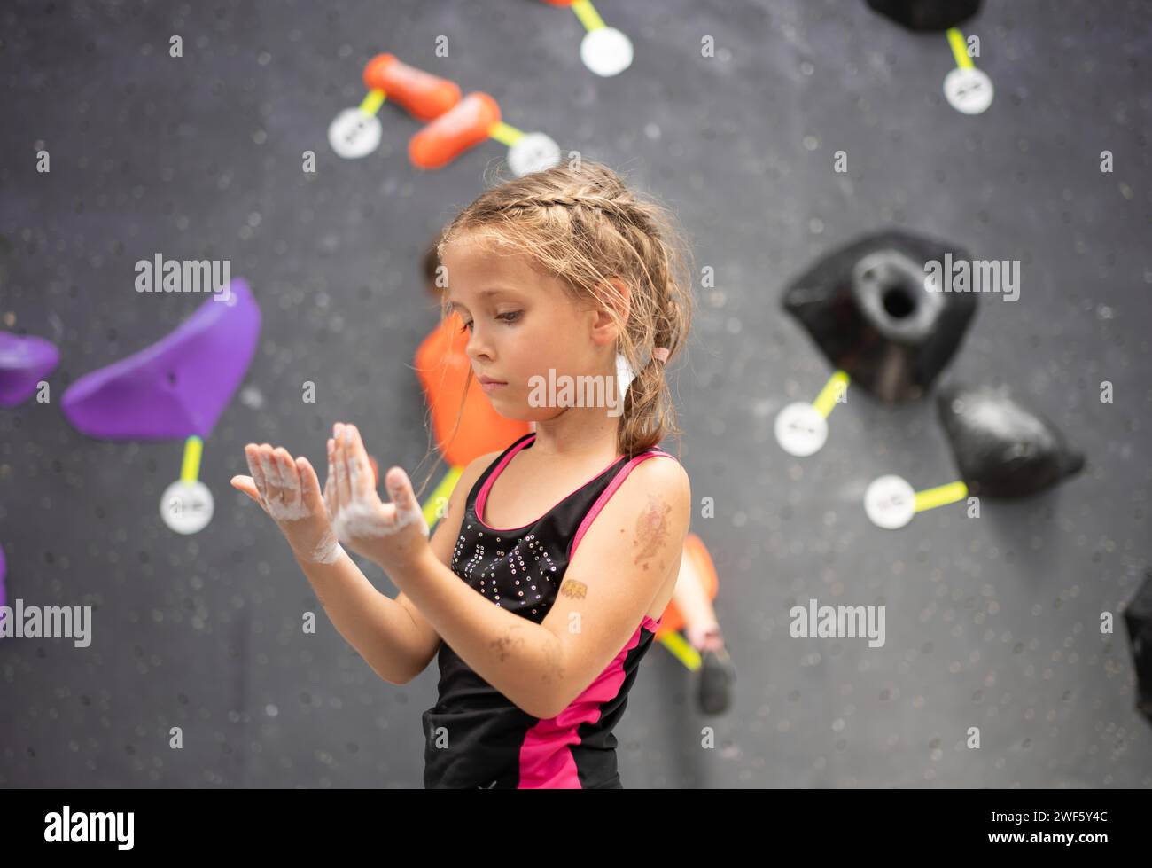 Cute adorable girl climber looking at hands coated with powder chalk ...