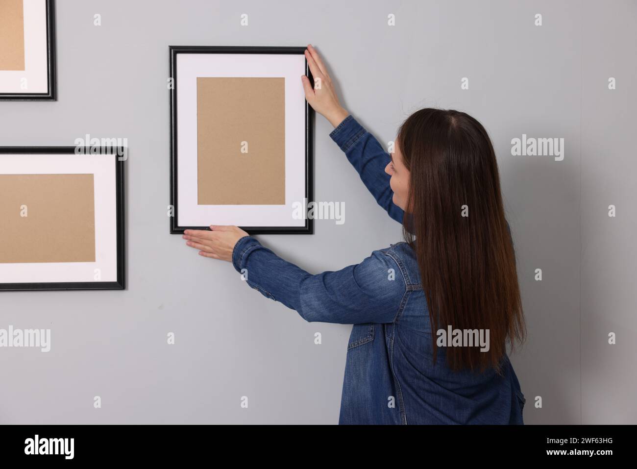 Woman hanging frame on the wall hi-res stock photography and images - Alamy