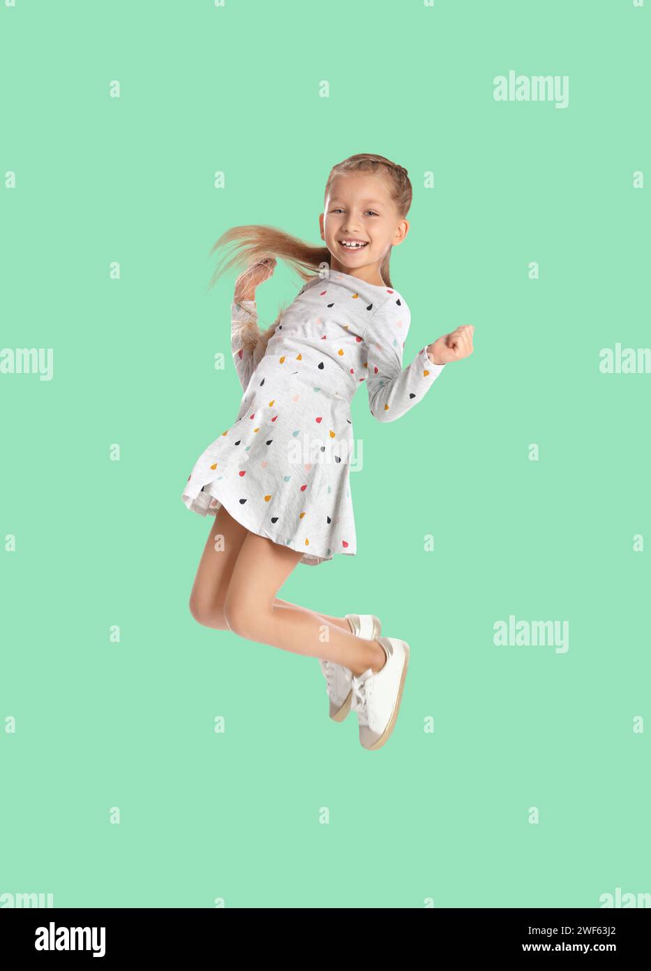 Happy cute girl jumping on aquamarine background Stock Photo - Alamy
