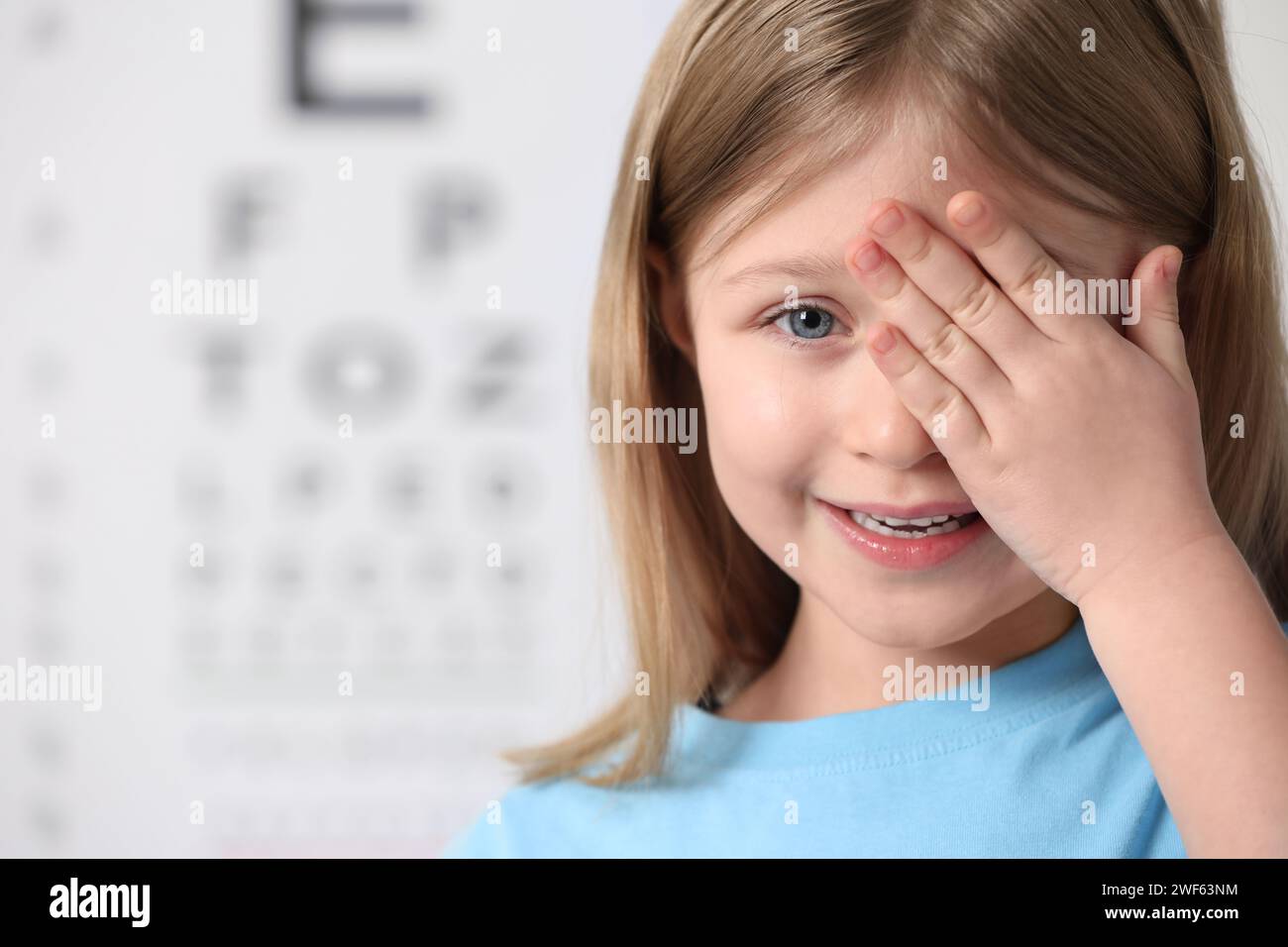 Little girl covering her eye against vision test chart Stock Photo - Alamy