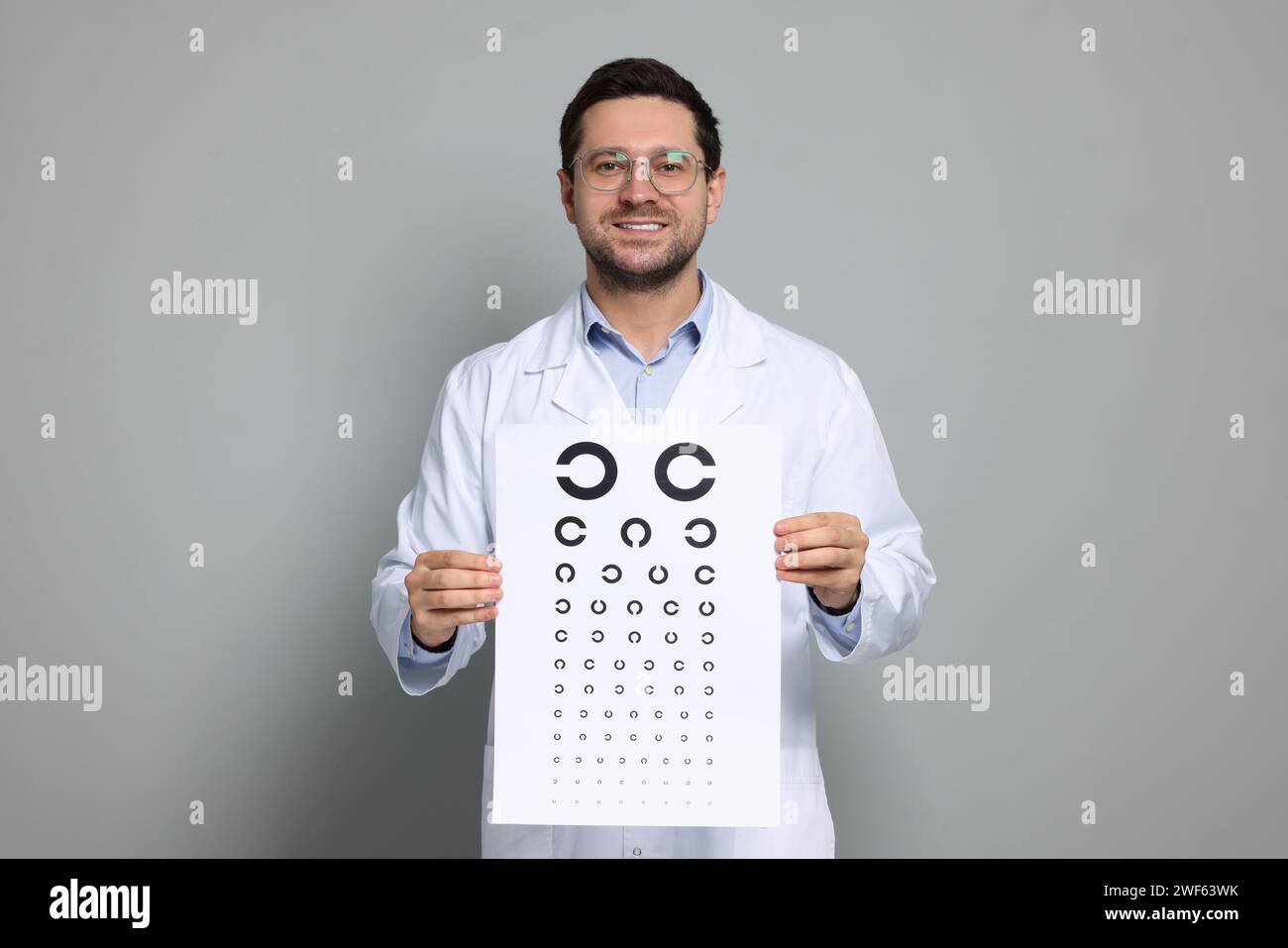 Ophthalmologist with vision test chart on gray background Stock Photo ...