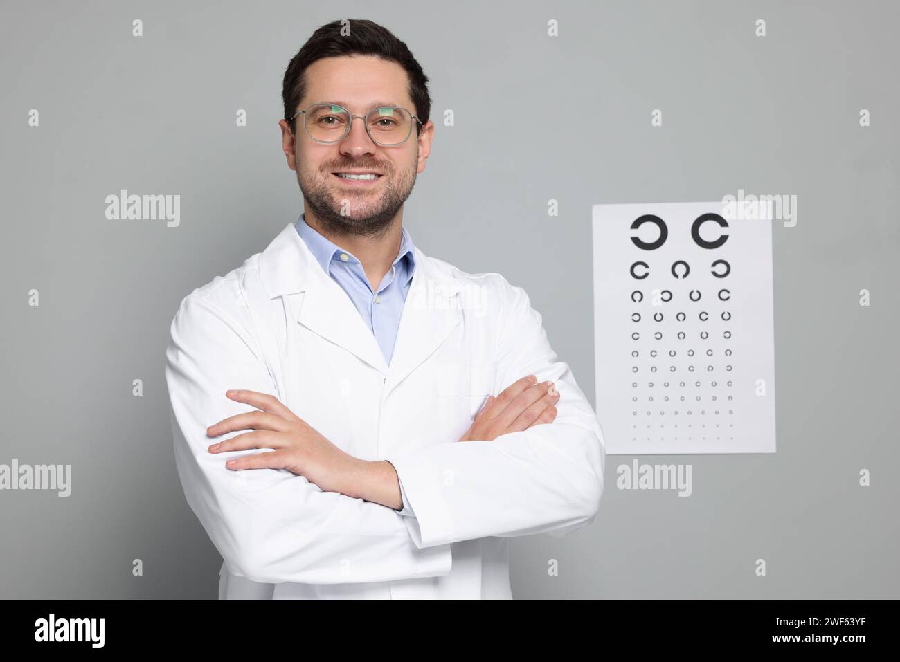 Ophthalmologist with vision test chart on gray background Stock Photo ...