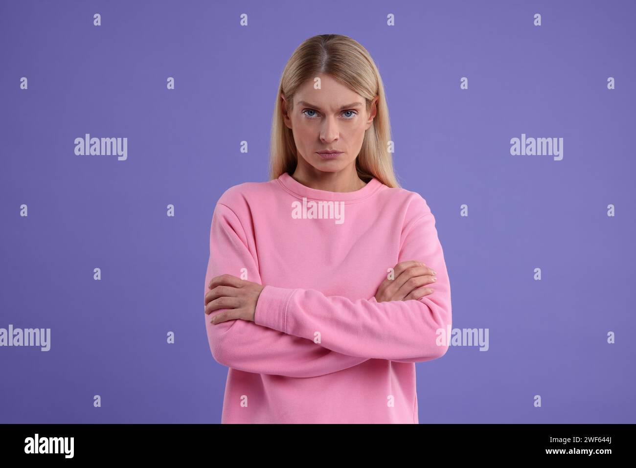 Resentful woman with crossed arms on purple background Stock Photo - Alamy