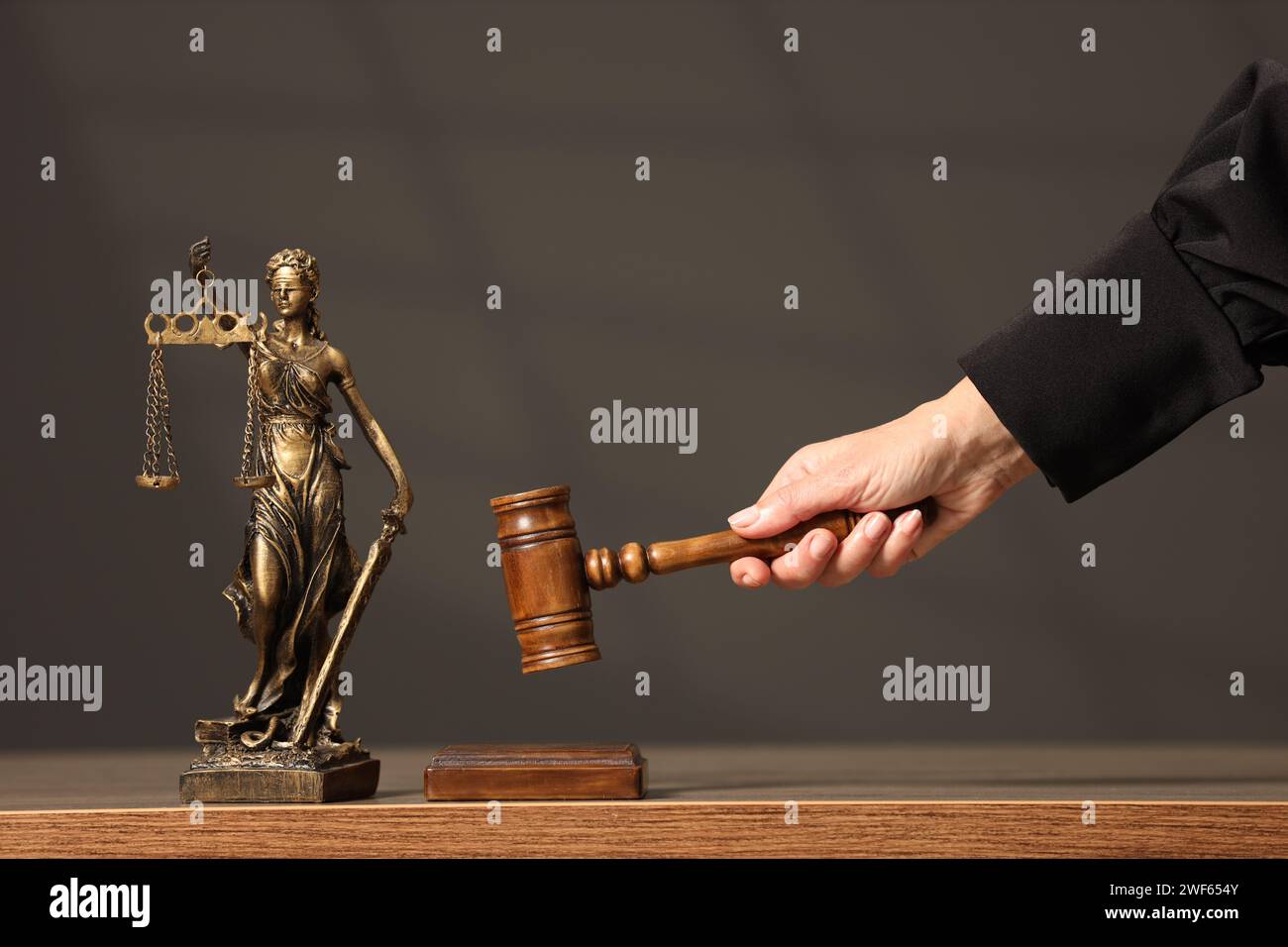 Judge striking mallet at wooden table against grey background, closeup ...
