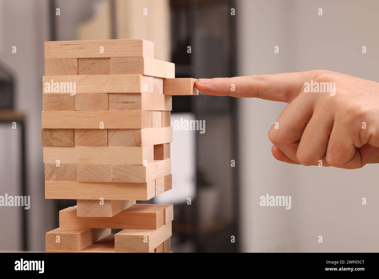 Playing Jenga. Man building tower with wooden blocks indoors, closeup ...