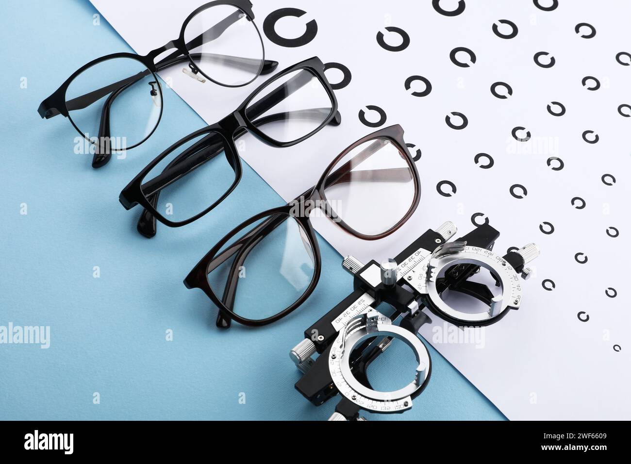 Vision test chart, glasses and trial frame on light blue background ...