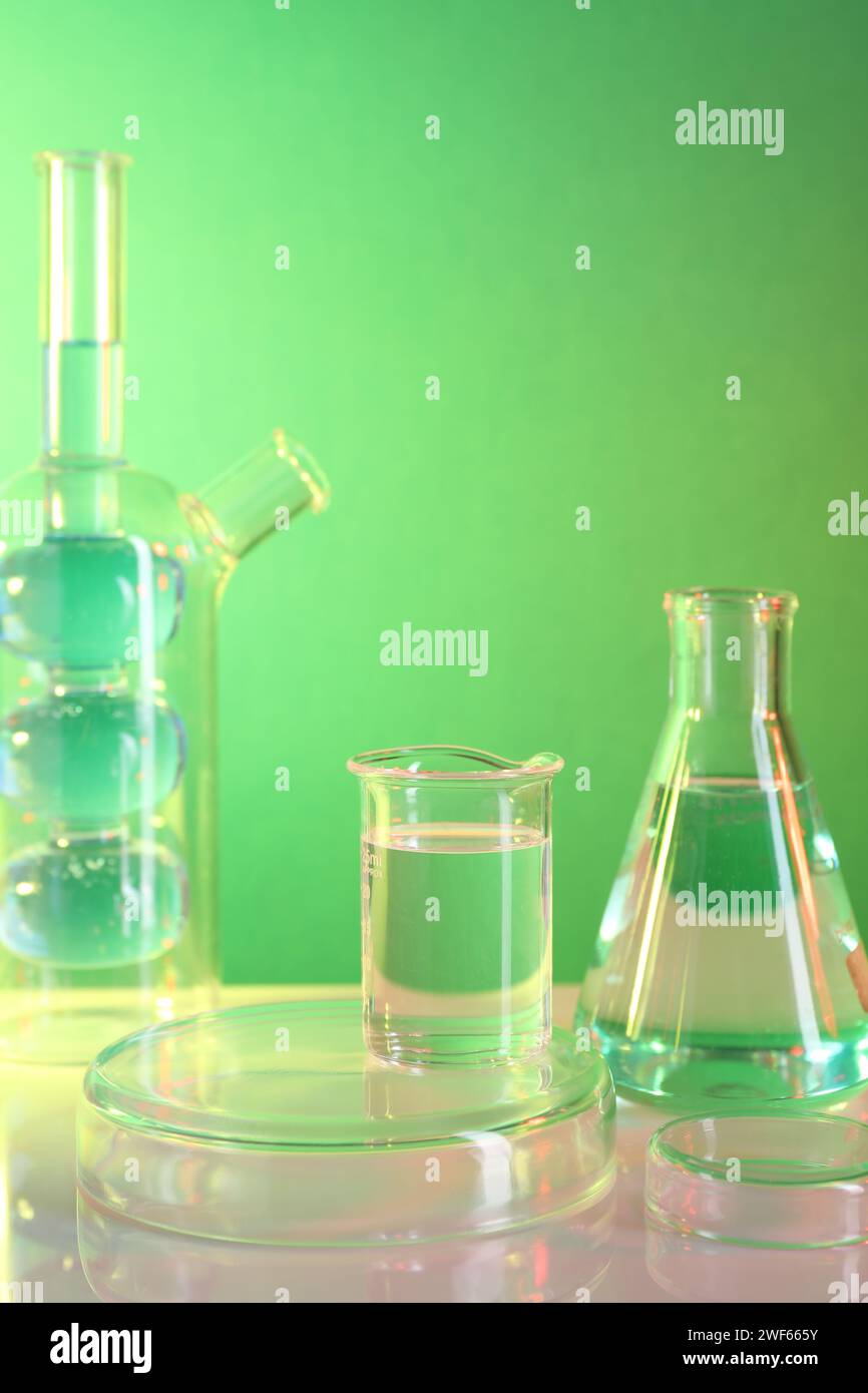 Laboratory analysis. Different glassware on table against green ...