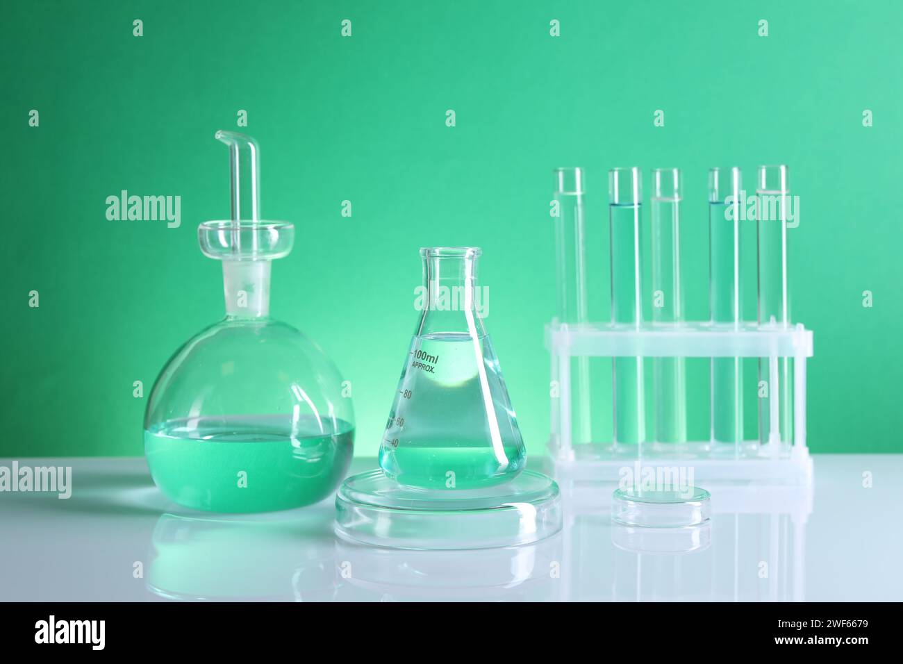 Laboratory analysis. Different glassware on table against green ...