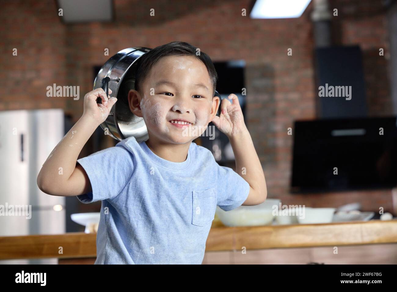 A happy little boy playing with a pot on his head Stock Photo - Alamy