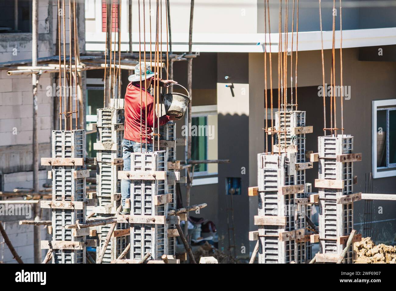 Worker pouring concrete to formwork frames at construction site to ...