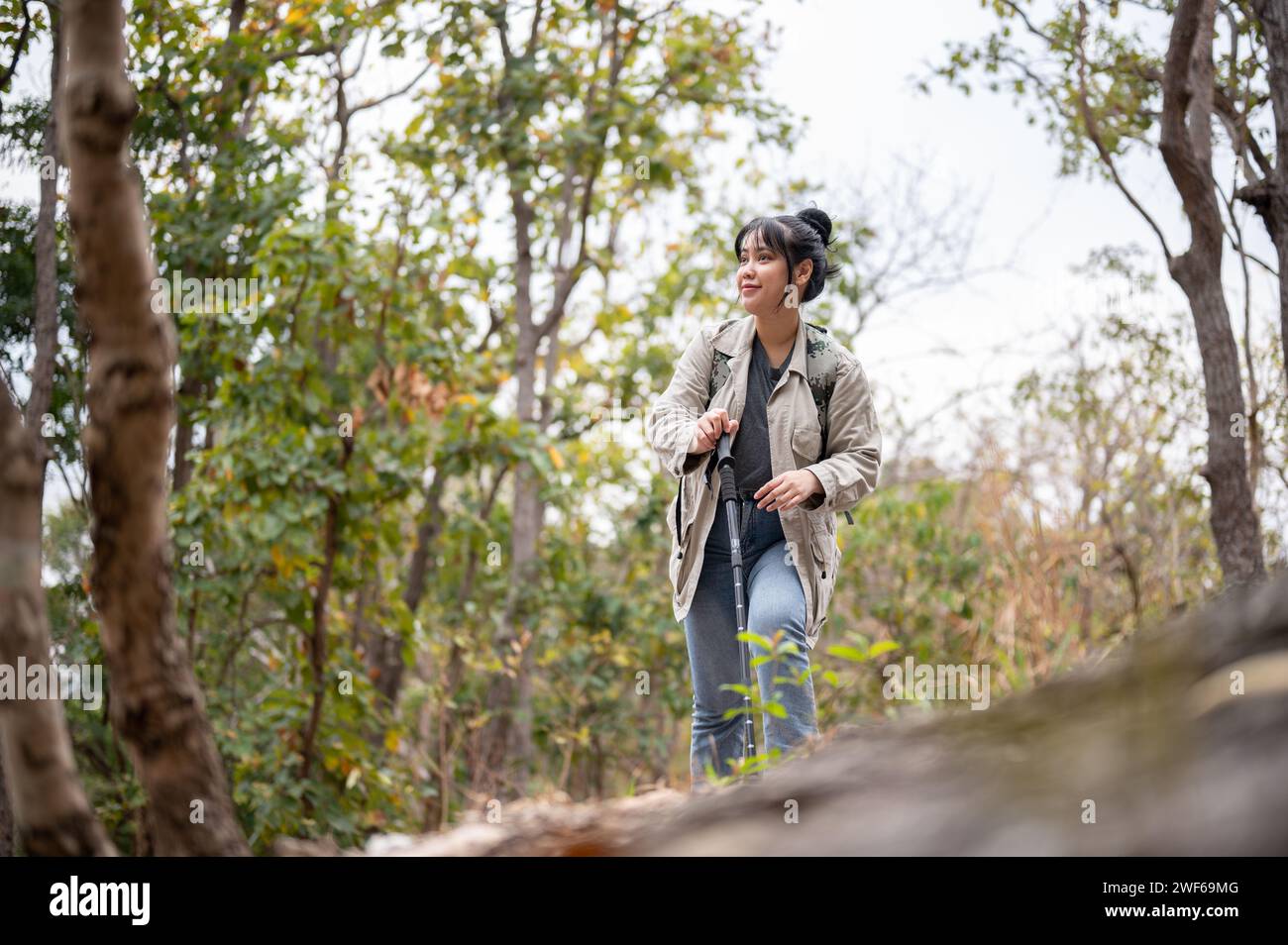 A positive Asian woman with a backpack is hiking on the mountain with a ...