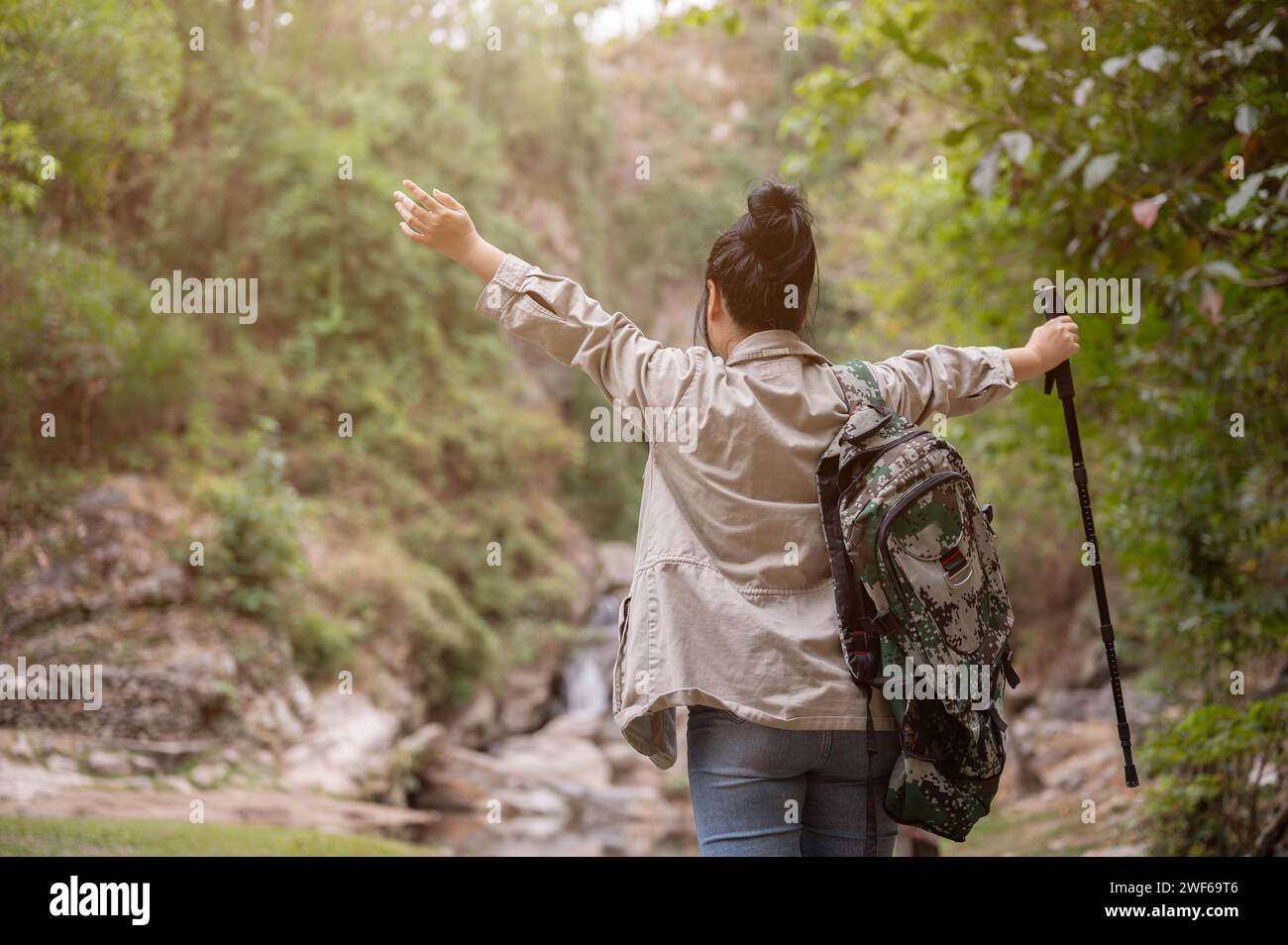 Back view image of a fun, excited Asian woman raising hands and ...