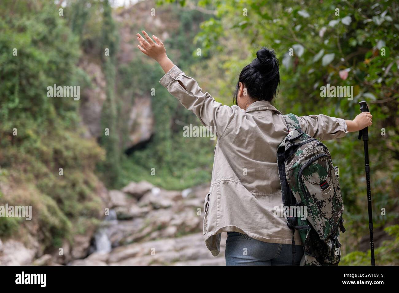 Back view image of a fun, excited Asian woman raising hands and ...