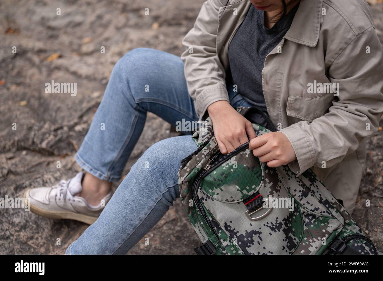 A cropped shot of a woman finding something in her backpack while ...