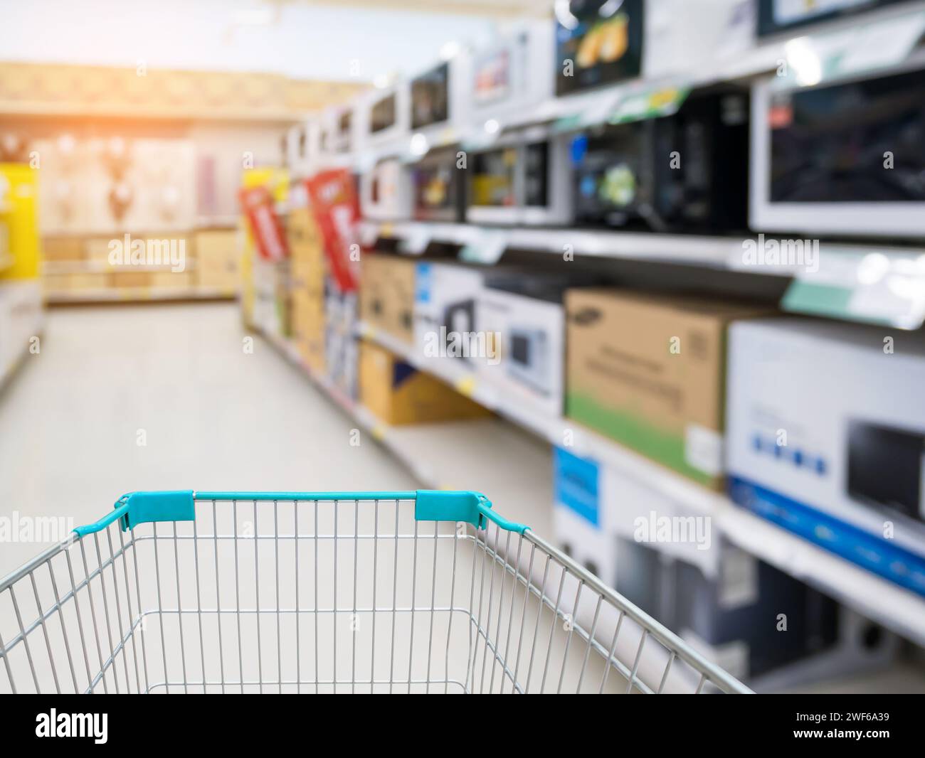 shopping cart with blur microwave shelf in electronics store aisle ...