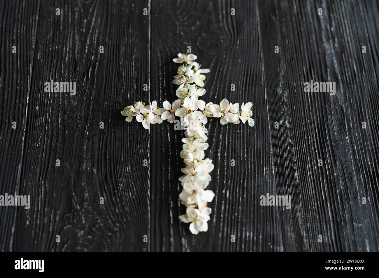 Cross with flowers on a wooden background with the inscription Christ ...