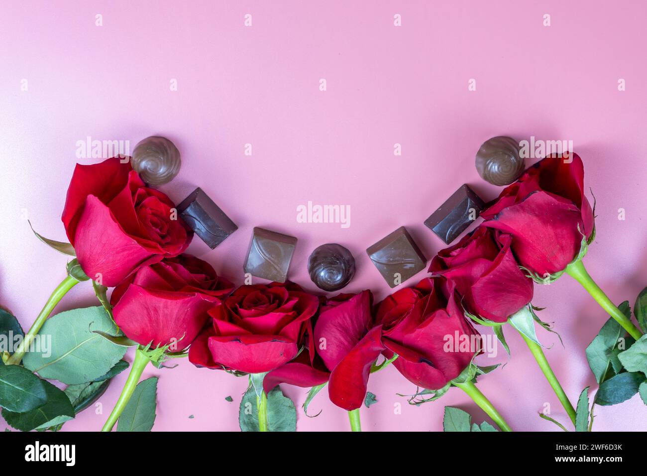 Delicious chocolate sweets and red roses on a pink background Stock ...