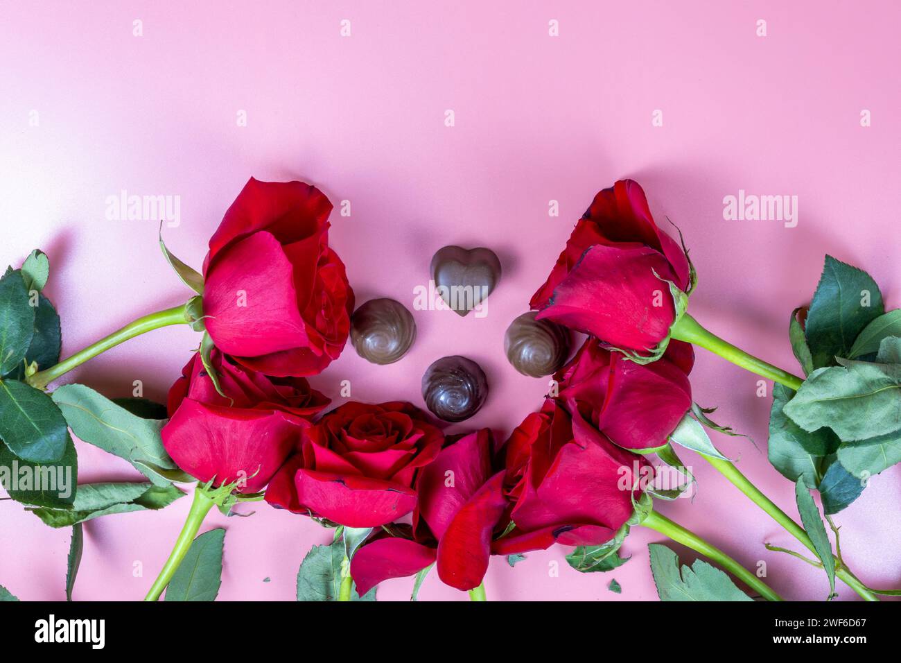 Delicious chocolate sweets and red roses on a pink background Stock ...