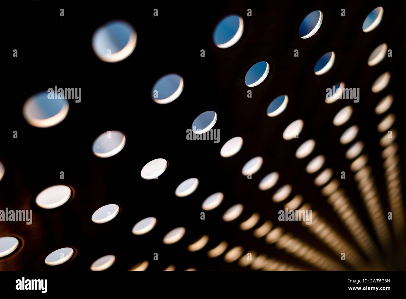 Abstract background of blurry dot hole metal wall with backlight behind ...