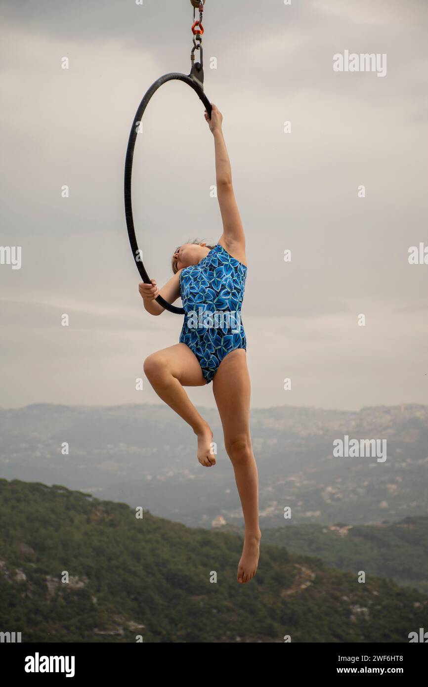 Little female gymnast performing on aerial hoop outdoors Stock Photo ...