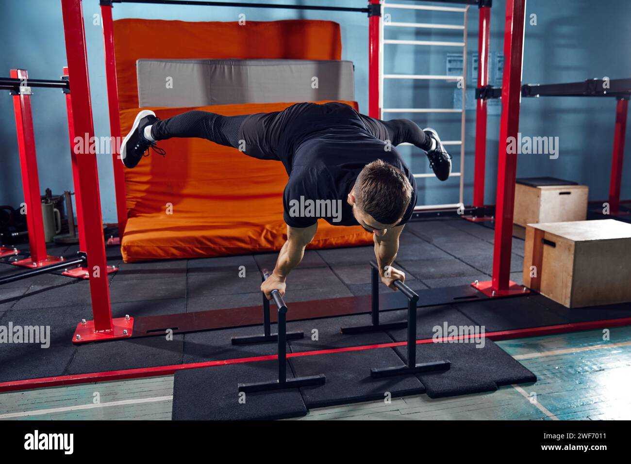 Muscular, athletic man in sportswear training in gym indoors, doing ...