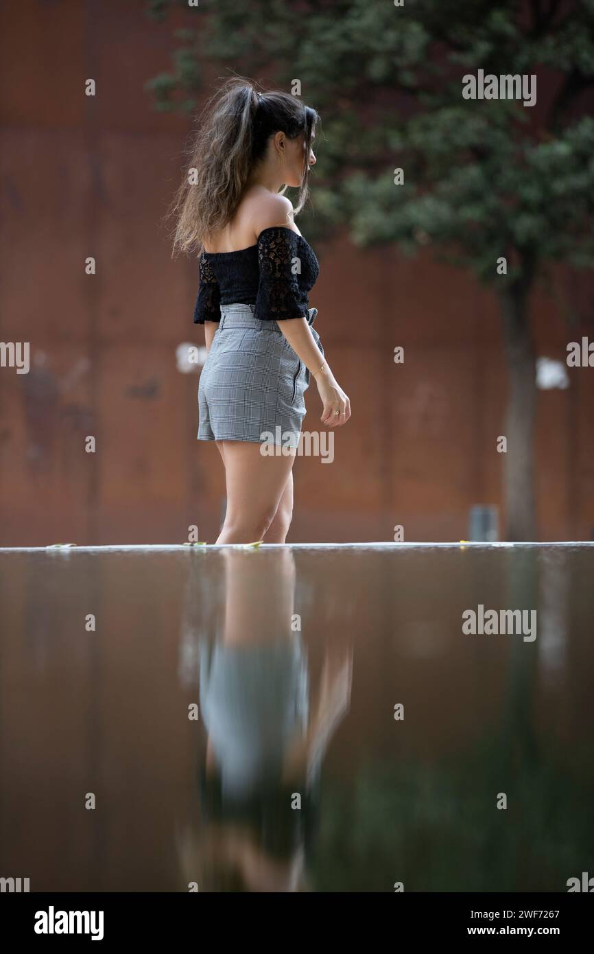 Side view of woman wearing shorts walking by the water Stock Photo - Alamy