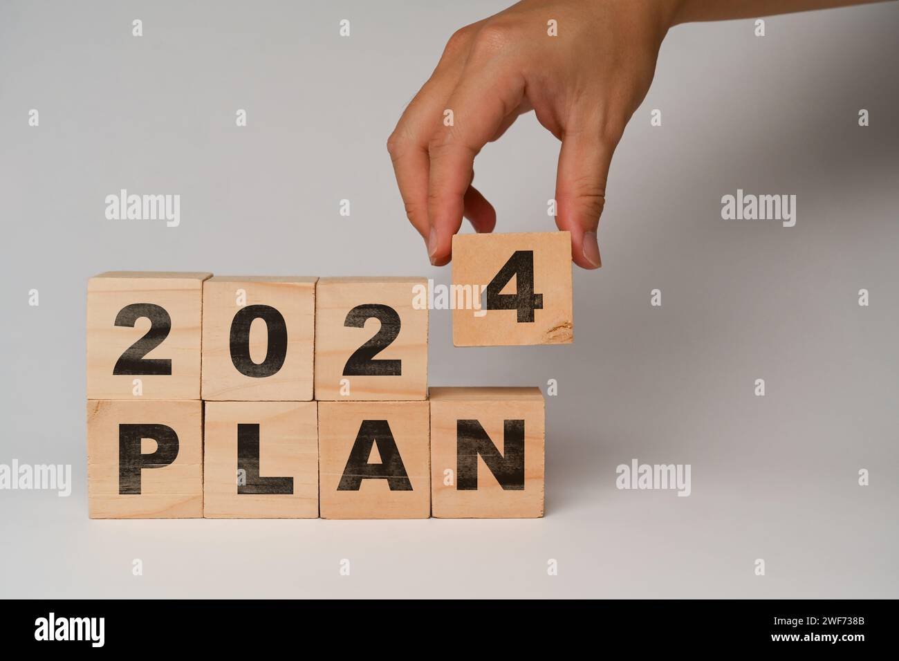 Hand placing wooden cube blocks with 2024 PLAN text on white background ...