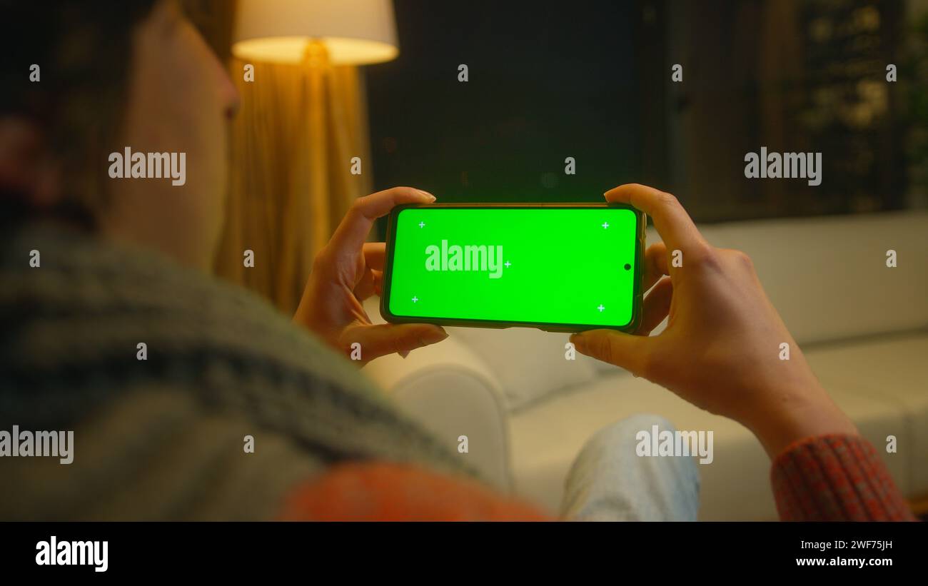 Young man watching video on his smartphone with green screen mock up ...