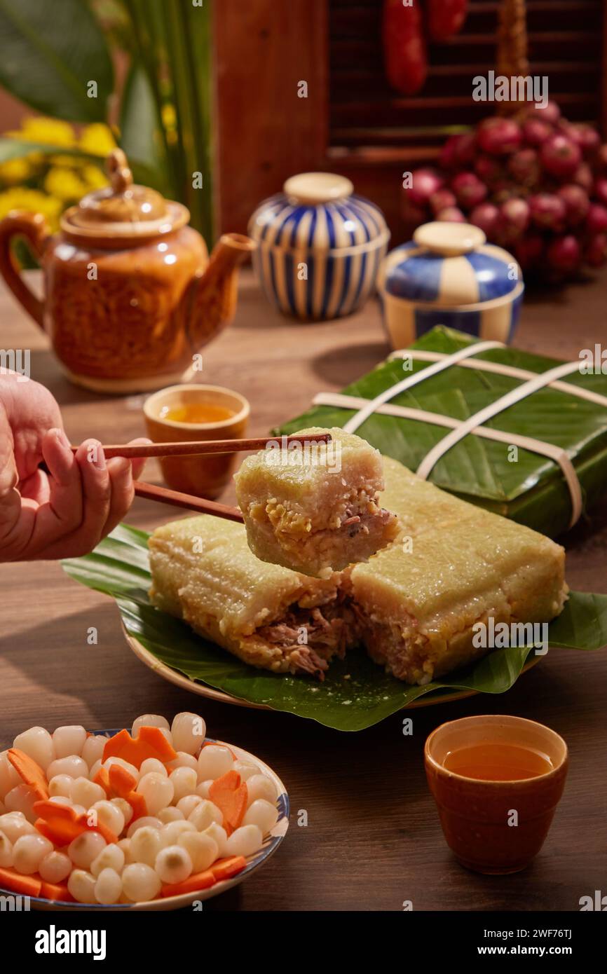Hand holding a piece of sticky rice cake (Chung cake) on tray Tet ...