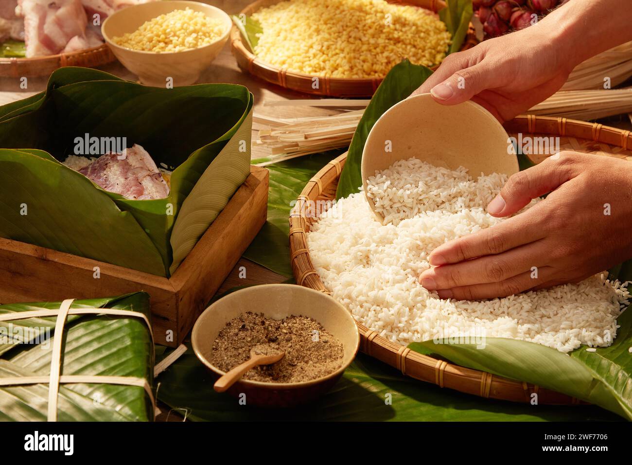 Hands putting white rice in box lined with dong leaves when making ...