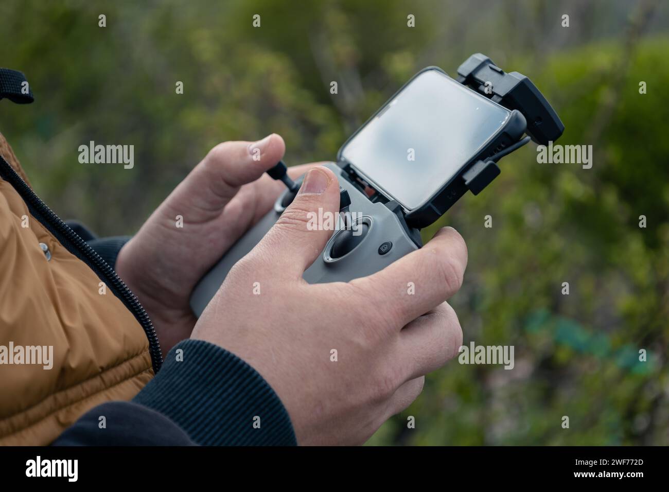Male hands hold a drone control panel with connected phone, close-up ...