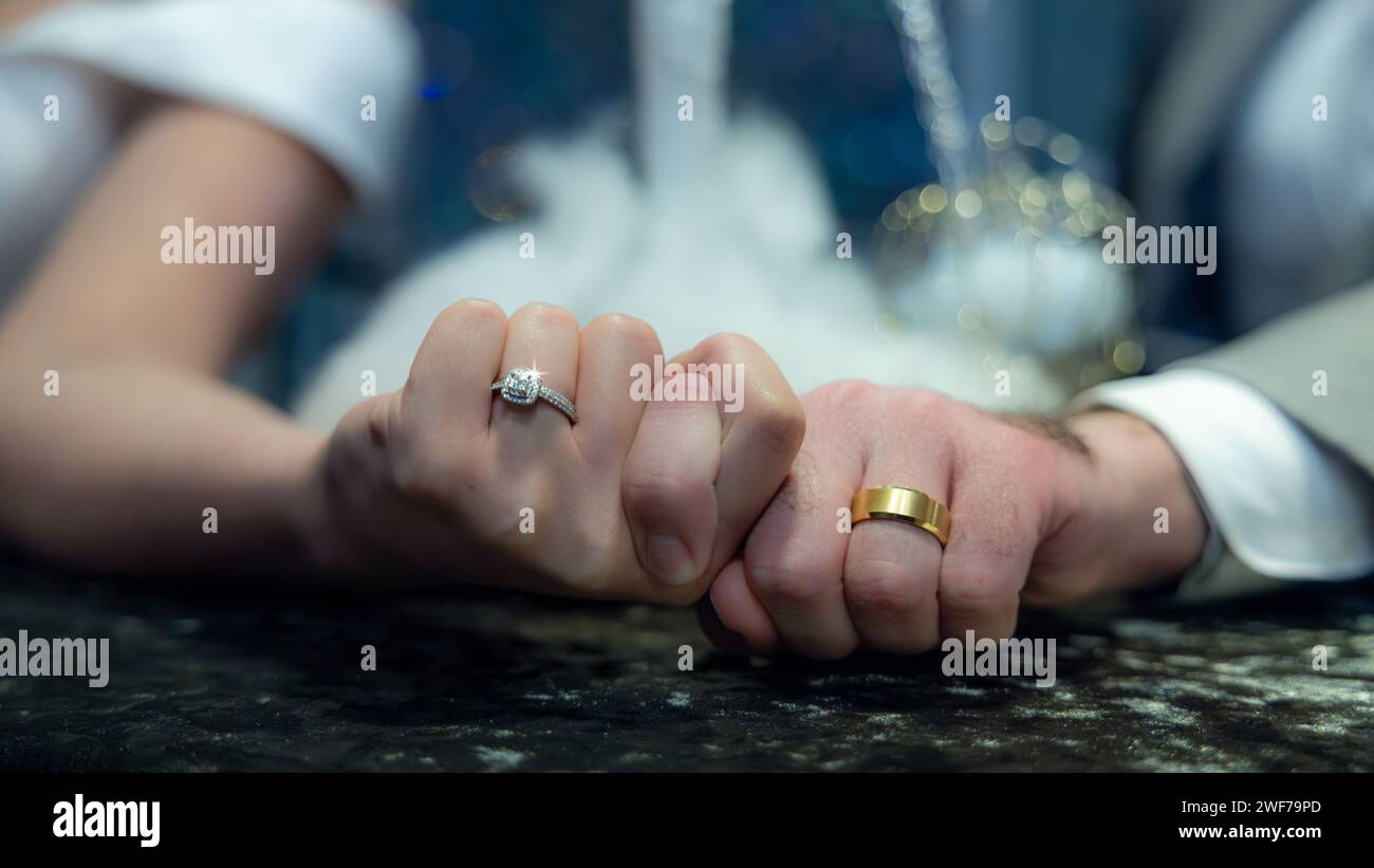 Two individuals touching hands, their wedding rings a symbol of their ...