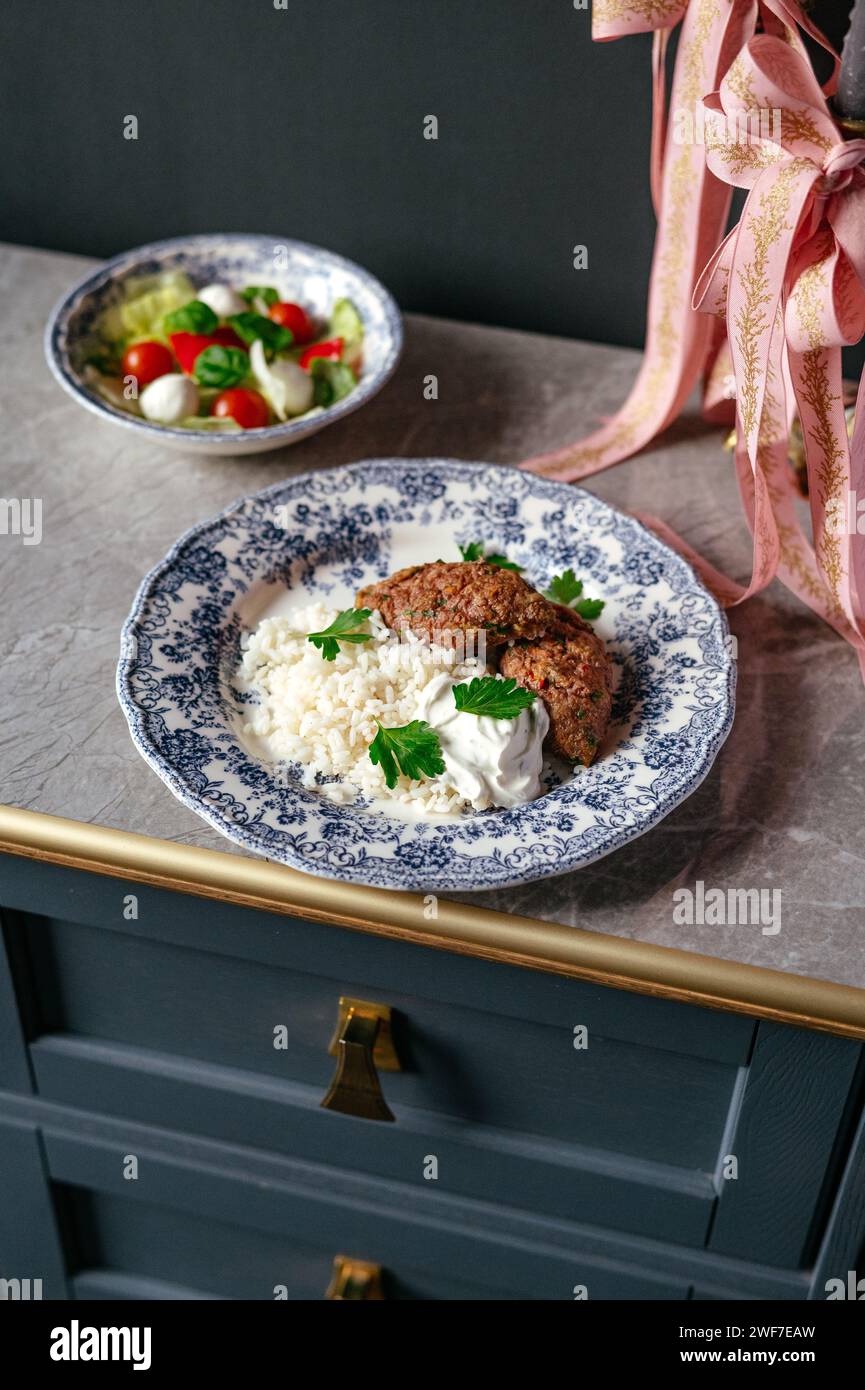 beef patty on a plate with a side dish of rice Stock Photo - Alamy