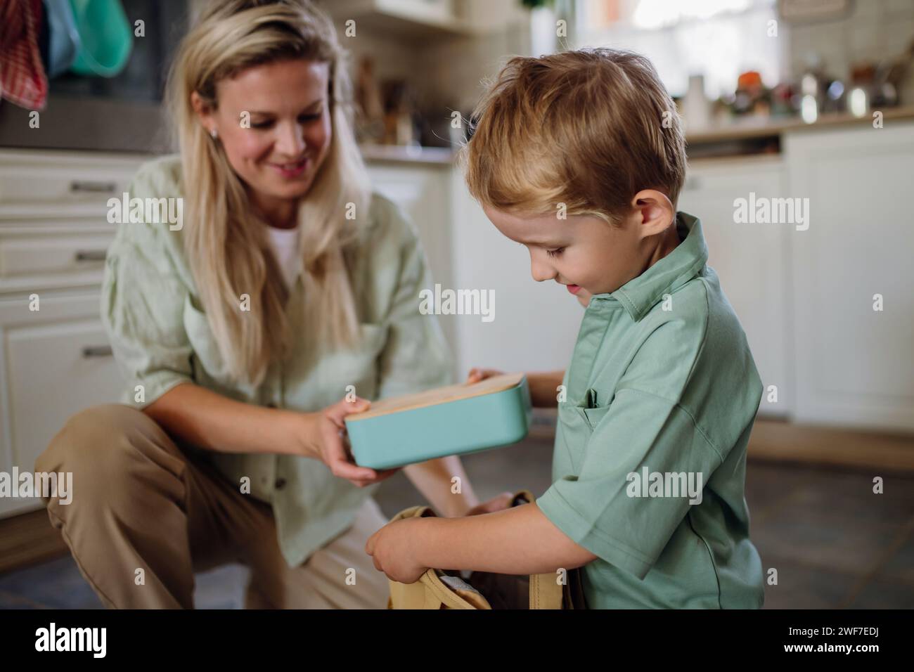 Mom packing snack for her son for school. Putting lunch box with ...