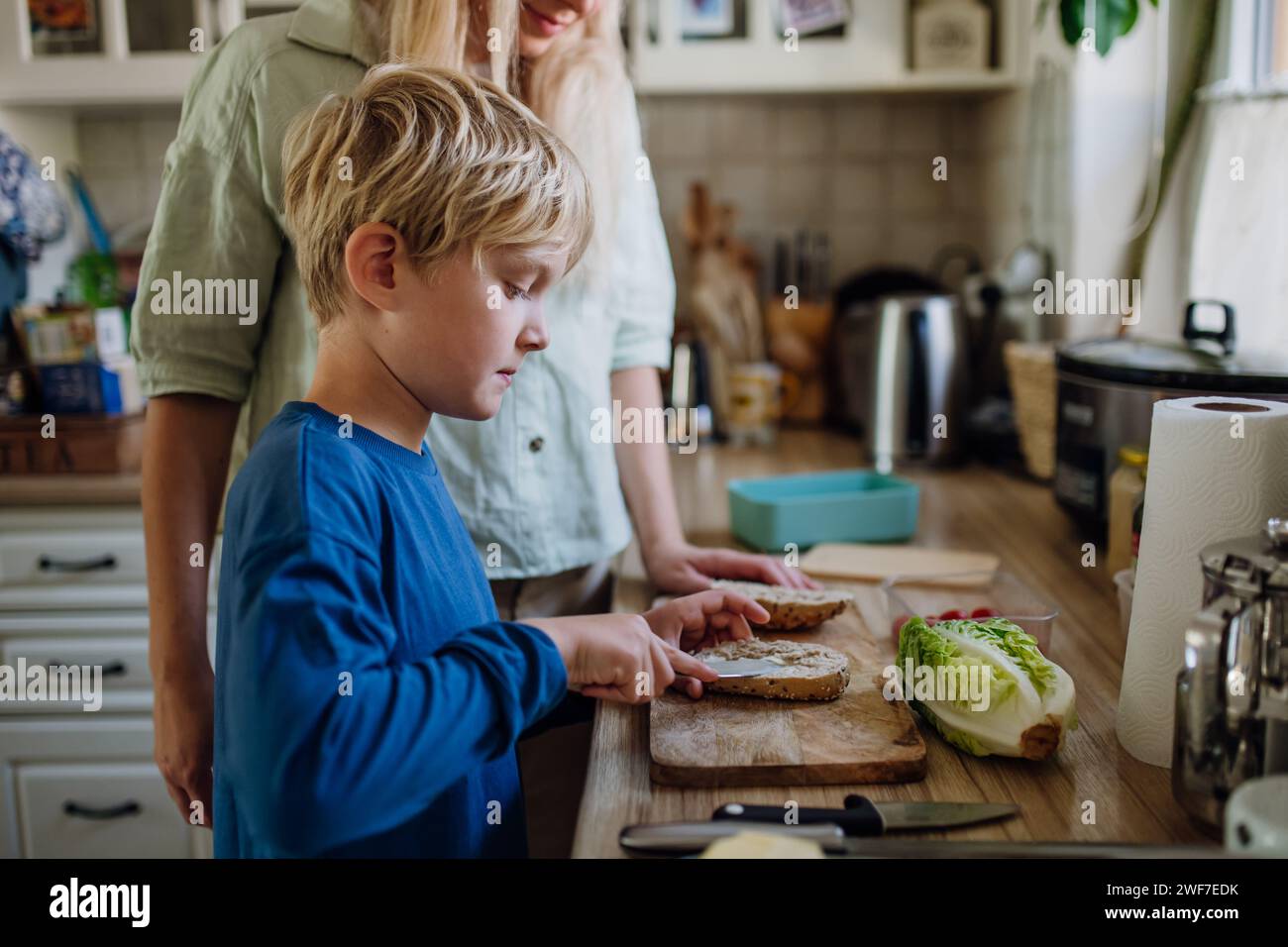 Boy helping mother to make school lunch in the kitchen. Preparing ...