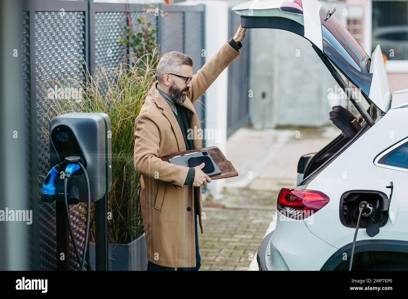 Businessman charging electric car before going to office. An electric ...