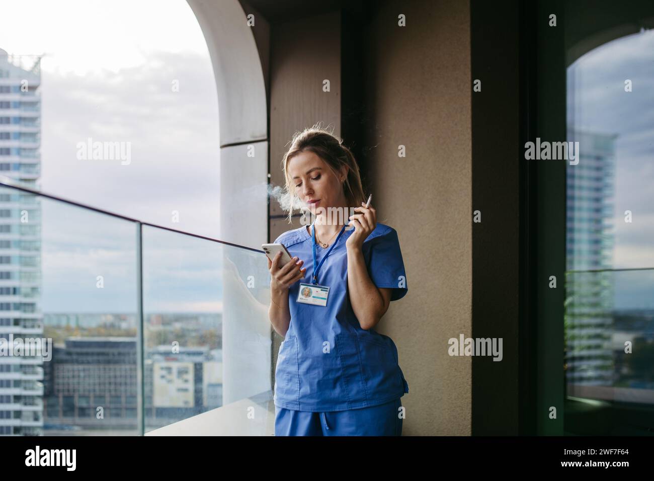 Female nurse smoking cigarette at balcony after work. Doctor feeling ...