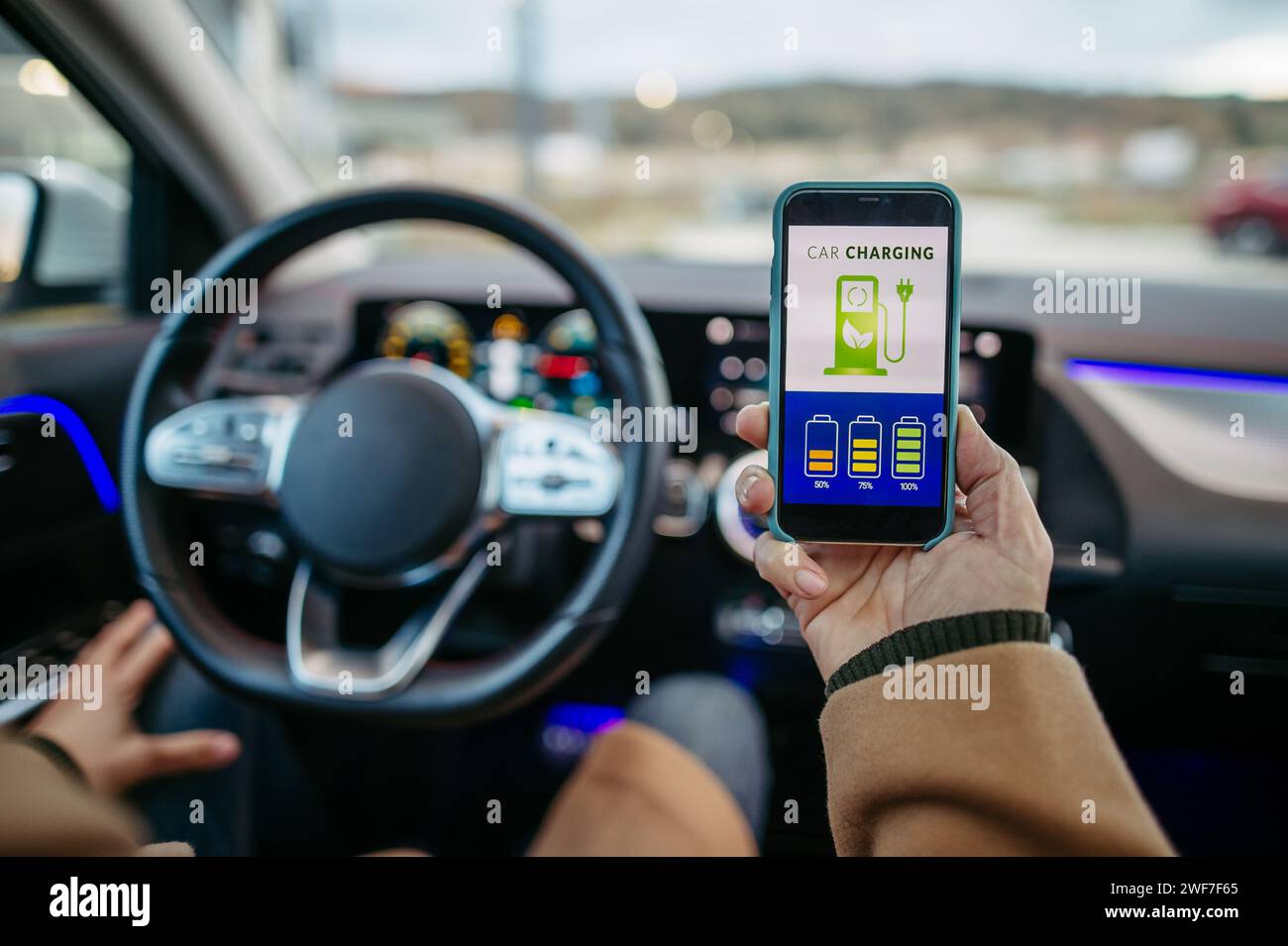 Close up of man using electric vehicle charging app, checking battery ...
