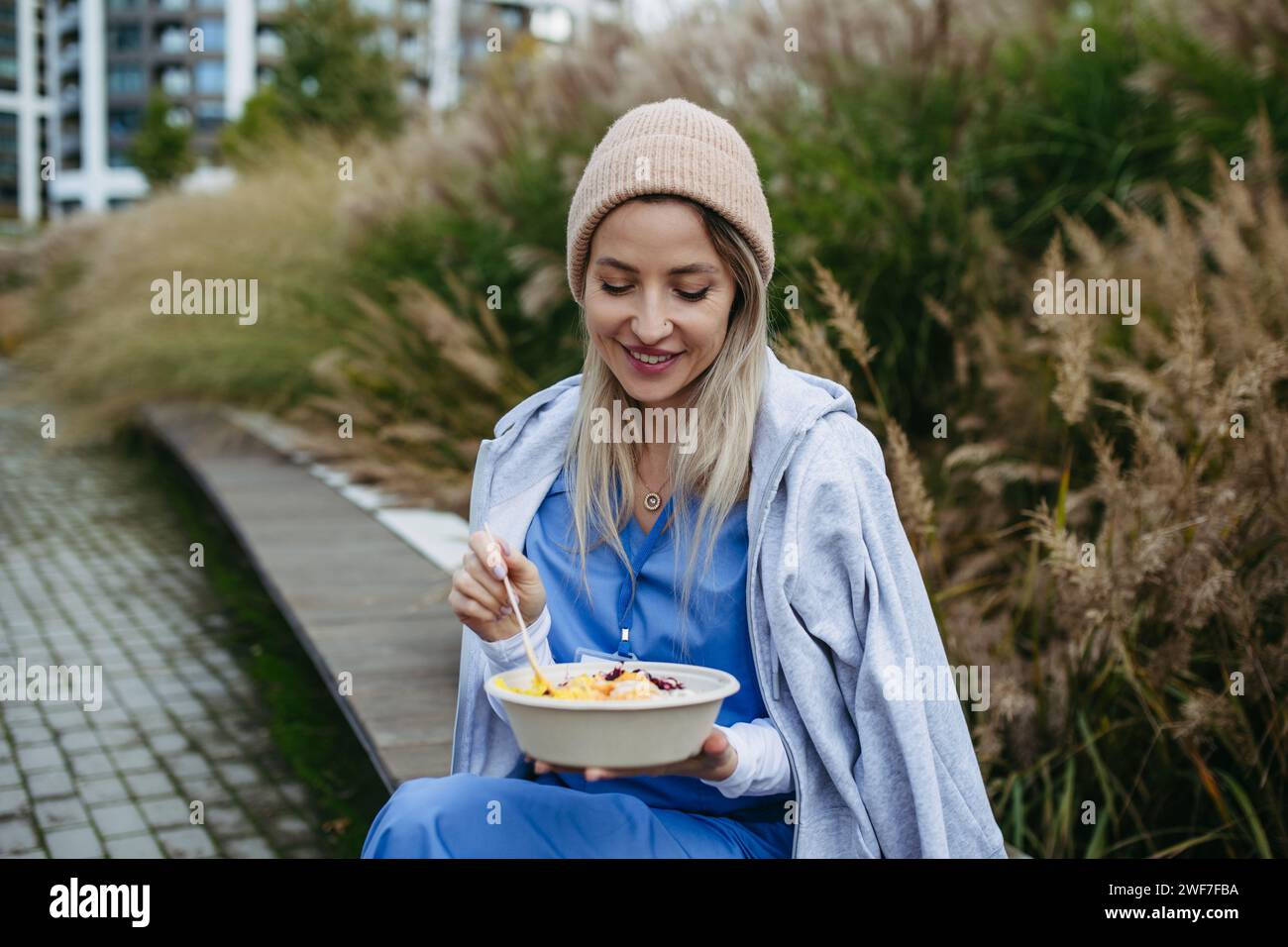 Nurse having healthy lunch, snack in front of hospital building, taking ...